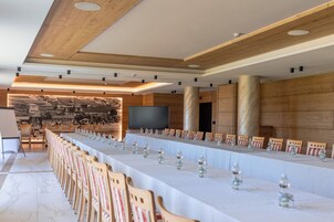 Sala de conferência com uma mesa comprida, cadeiras e uma tela grande.