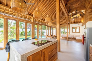 Uma cozinha espaçosa com uma ilha grande, vigas de madeira e vista para uma piscina.