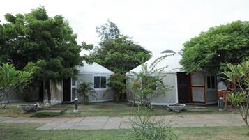 Bairro residencial com duas casas, uma com porta e janela visíveis, e outra com a porta entreaberta. Há árvores e um pequeno jardim com um caminho.
