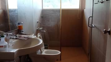 Casa de banho compacta com lavatório, sanita e chuveiro.