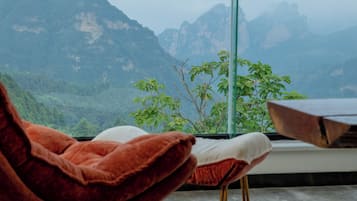 Interior moderno com vista para montanhas através de uma grande janela.