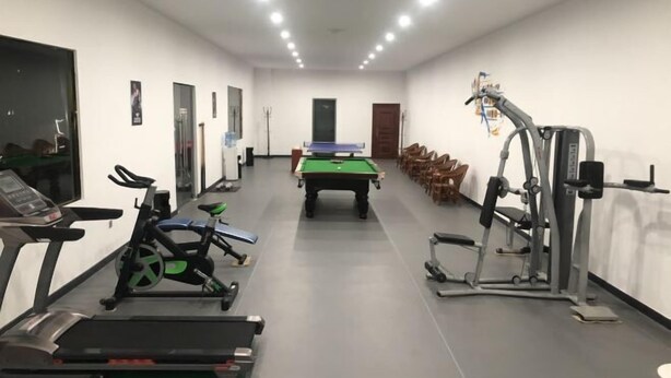 Uma academia com equipamentos de exercícios, mesa de bilhar e sinuca.