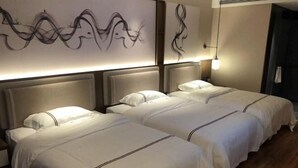 Quarto de hotel com duas camas, um design moderno de cabeceira e uma luminária fixada na parede.