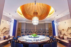 Uma sala de conferência com uma mesa redonda, cadeiras e um arranjo floral central.