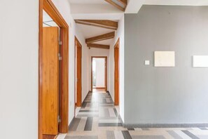Um corredor com portas de madeira, um chão estampado e uma parede cinzenta com duas placas.