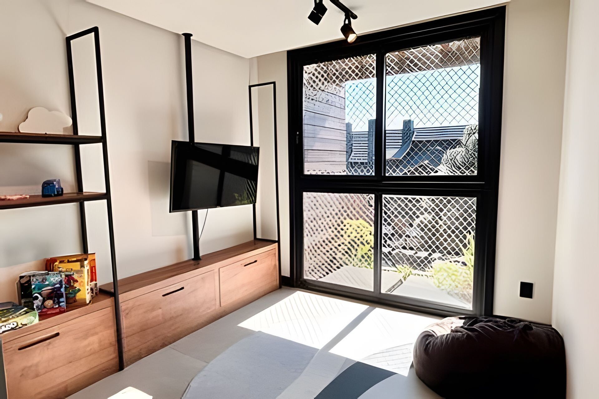 Quarto moderno com uma grande janela, televisão e cómoda de madeira.