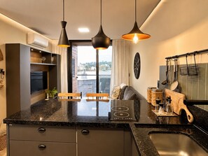 Uma cozinha moderna com ilha central, eletrodomésticos embutidos e iluminação pendente.