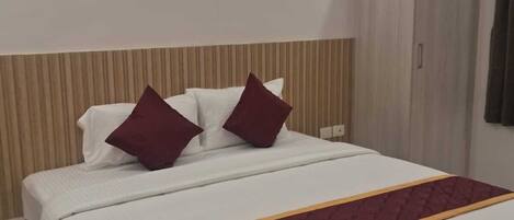 Quarto de hotel com cama, mesa de cabeceira, guarda-roupa e cortina.