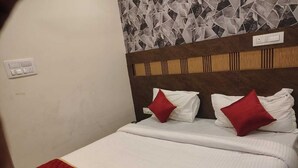 Quarto de hotel com uma cama, um espesso edredom acolchoado vermelho e uma cabeceira com padrão geométrico de azulejos.