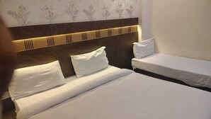 Quarto de hotel com duas camas, cabeceira com iluminação embutida e papel de parede estampado com motivos florais.