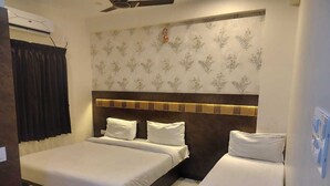Quarto de hotel com uma cama grande, uma cama menor, cabeceira com painel decorativo, ar-condicionado fixado na parede e cortina.