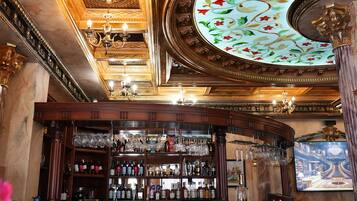 Um espaço de bar luxuoso, com detalhes ornamentais no teto e um teto de vidro decorativo.