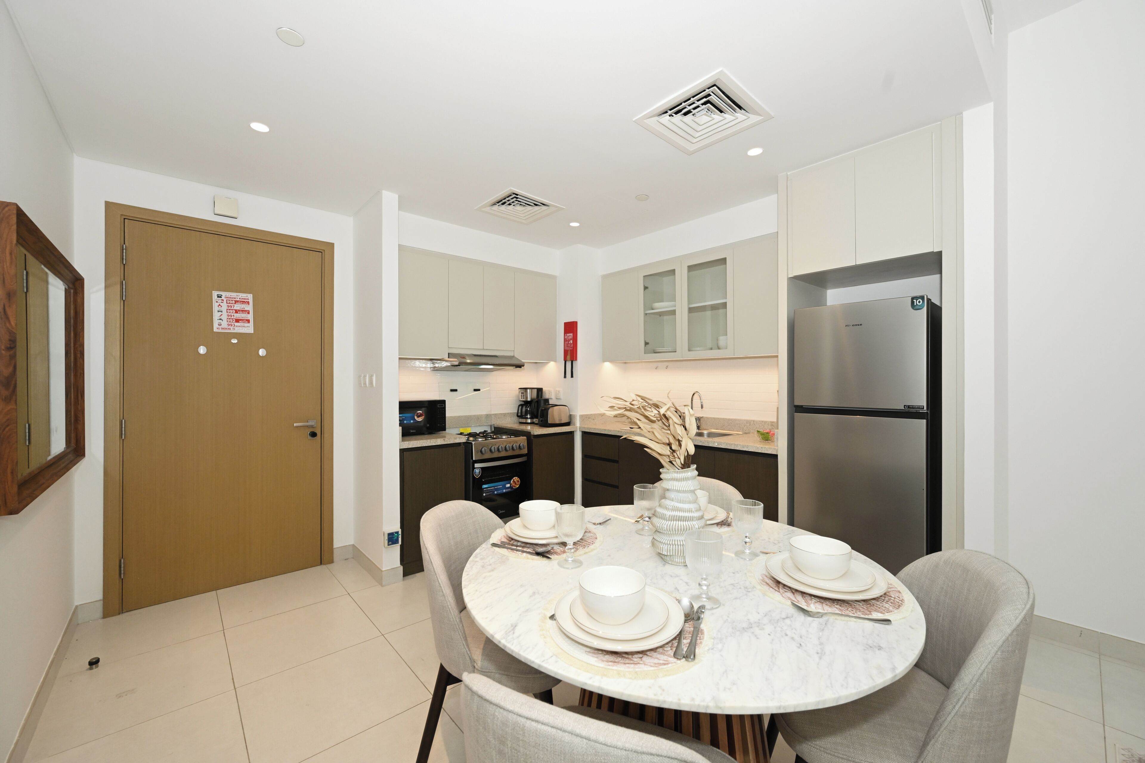 Uma cozinha moderna com forno embutido, geladeira e sala de jantar com mesa redonda posta para dois.