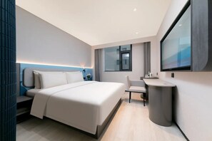 Quarto de hotel moderno com uma cama grande, uma escrivaninha e uma janela ampla.