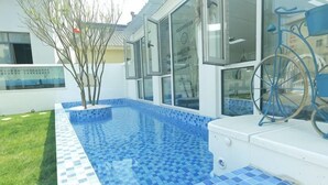Piscina com azulejos azuis, uma árvore e um detalhe decorativo de roda de bicicleta.