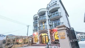 Um hotel com vários andares, entrada imponente, varandas e acesso por portão.