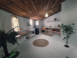 Uma cozinha compacta com teto de madeira, uma mesa de jantar e um espaço de bar.