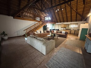 Uma área de estar ampla com teto alto, escada e espaço para cozinha.