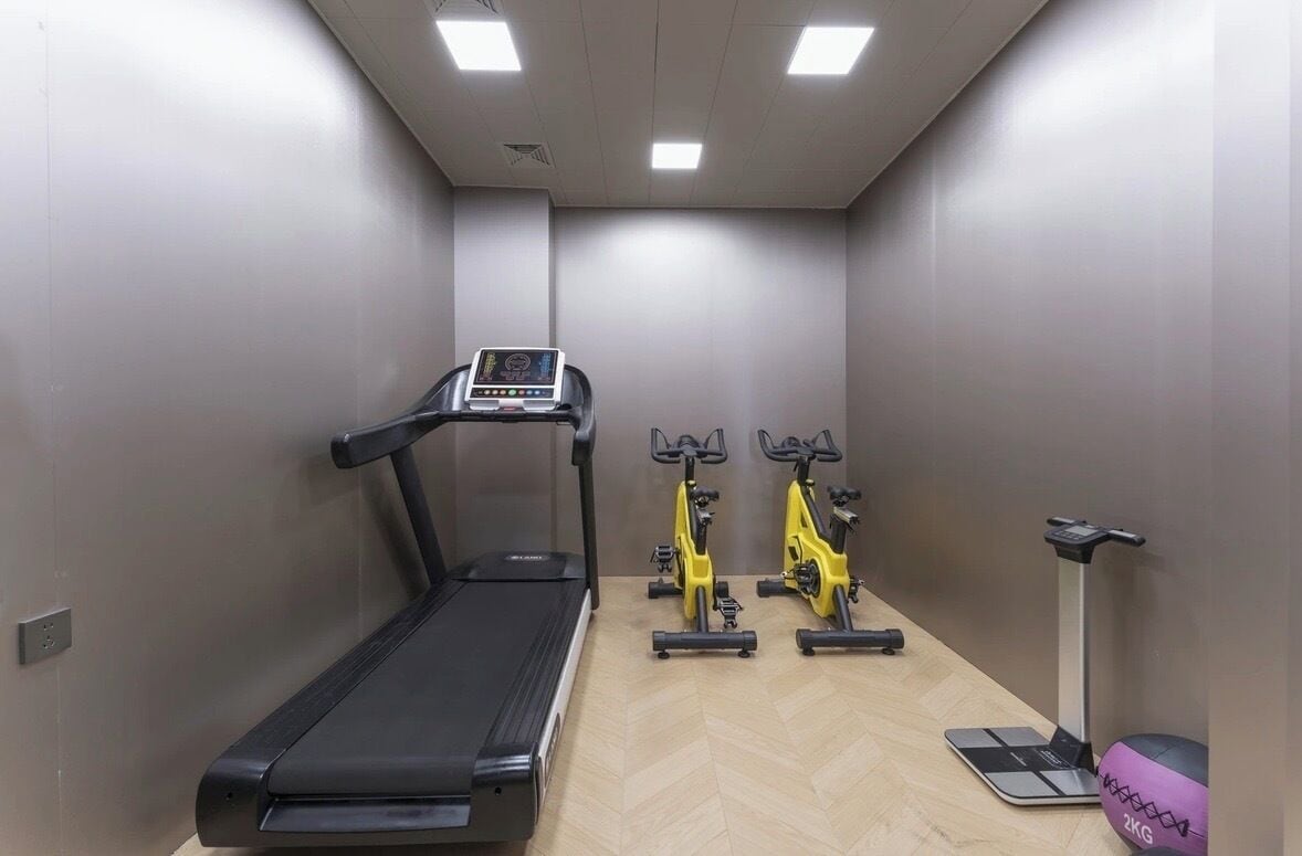 Uma academia com esteira, bicicletas ergométricas e plataforma para exercícios.