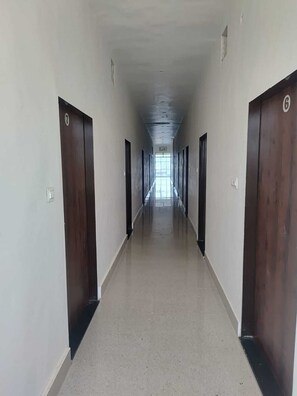 Um corredor comprido e estreito com portas de ambos os lados que dão para quartos individuais.