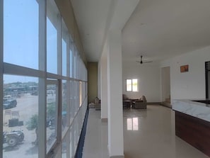 Um quarto espaçoso com uma grande janela, ventoinha no teto e bancada de mármore.
