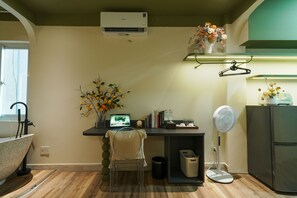 Cozinha equipada com ar condicionado, um laptop em uma mesa, um vaso com flores, um ventilador e uma geladeira.