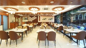 Um restaurante com várias mesas e cadeiras, teto de madeira e vista através de grandes janelas.