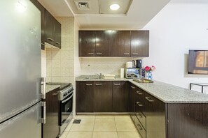 Uma cozinha moderna com armários de madeira escura, geladeira de aço inoxidável, forno embutido e bancada de granito.