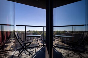 Uma varanda com mesa e cadeiras, com vista para um horizonte urbano com edifícios e céu limpo.