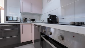 Uma cozinha moderna com eletrodomésticos de aço inoxidável, micro-ondas, chaleira e cafeteira.