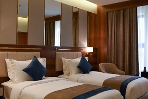 Quarto de hotel com duas camas, um espelho grande e vista para o exterior.