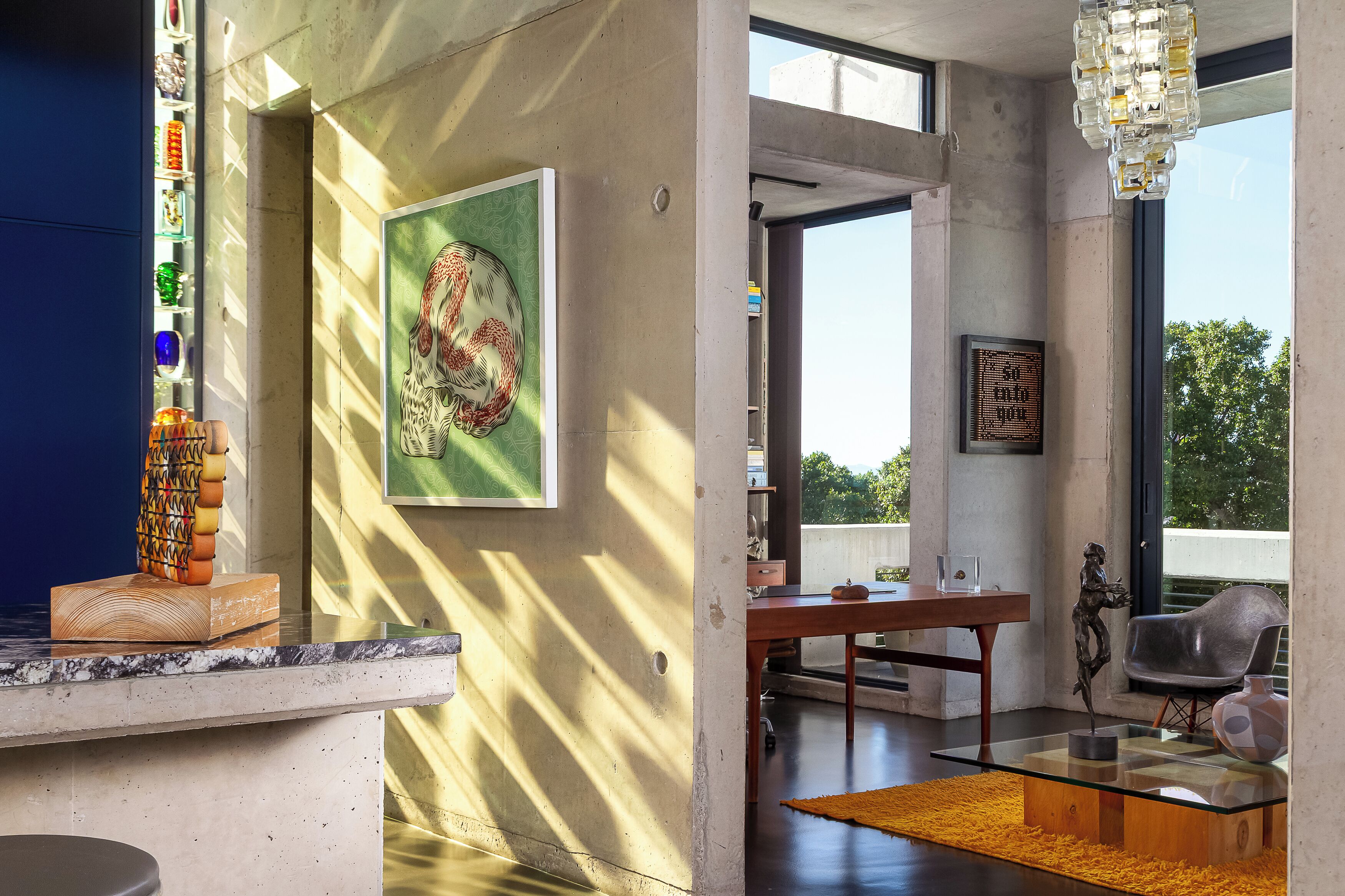 Um interior moderno com uma mesa de vidro, uma escultura e um quadro.