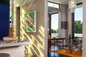 Um interior moderno com uma mesa de vidro, uma escultura e um quadro.