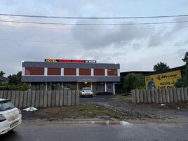 Um hotel chamado 'Hotel Krishna Garden', com placa indicando quarto com ar condicionado, cerca de concreto e um carro estacionado na frente.