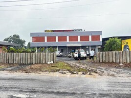 Um hotel chamado 'Krishna Garden' com quarto com ar condicionado, cerca de concreto e estrada de terra à frente.