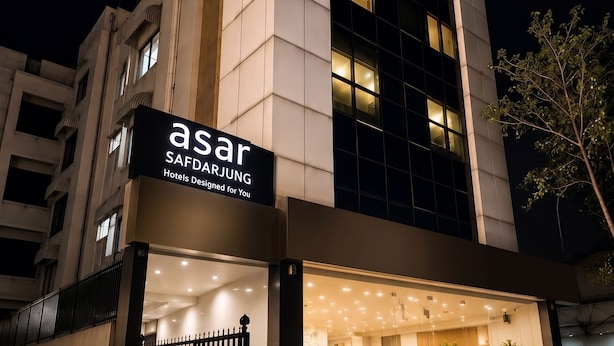 Fachada moderna de hotel com uma placa de destaque para 'asar SAFDARJUNG Hotels Designed for You' à noite.