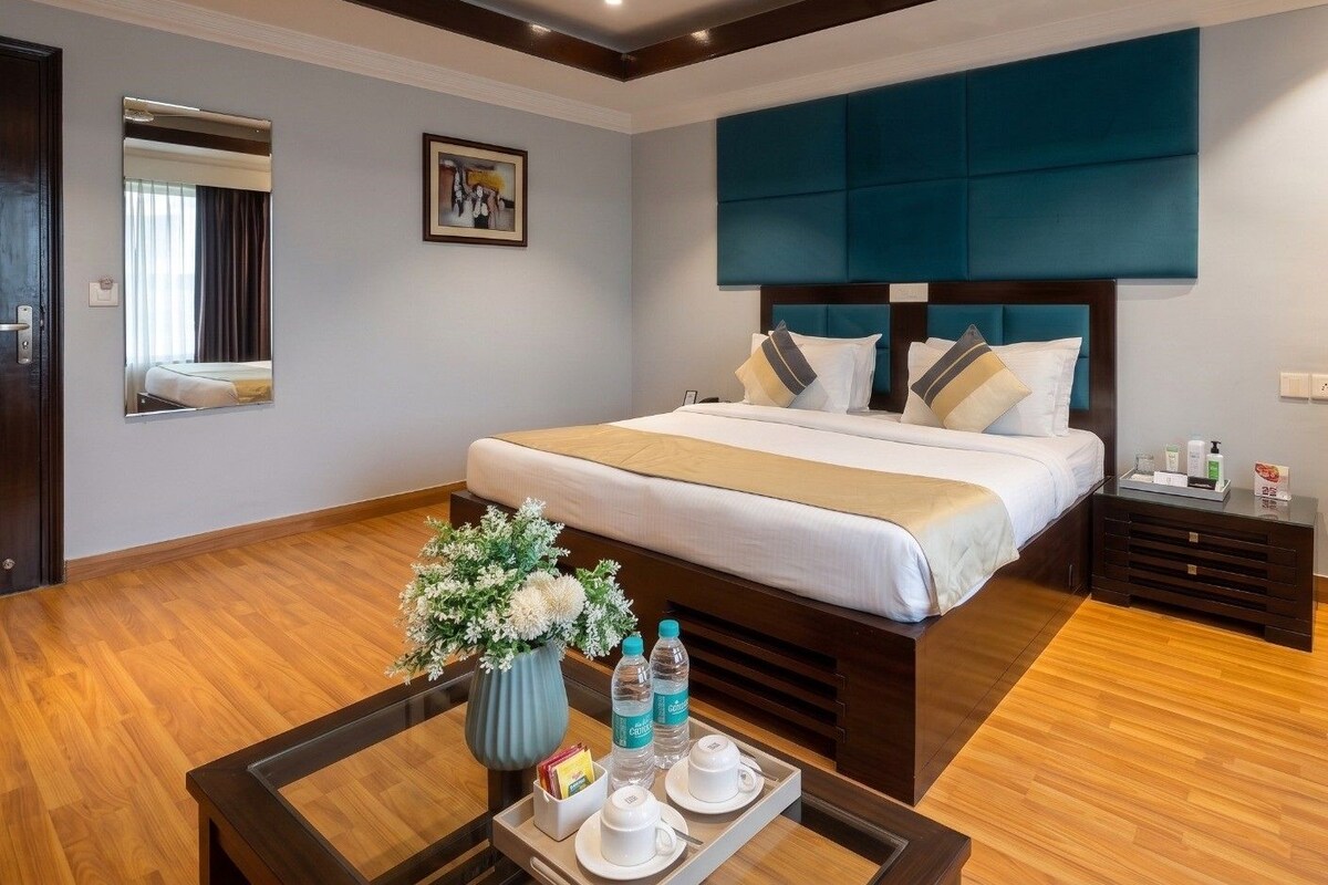 Quarto de hotel com cama, mesa de cabeceira e espelho.