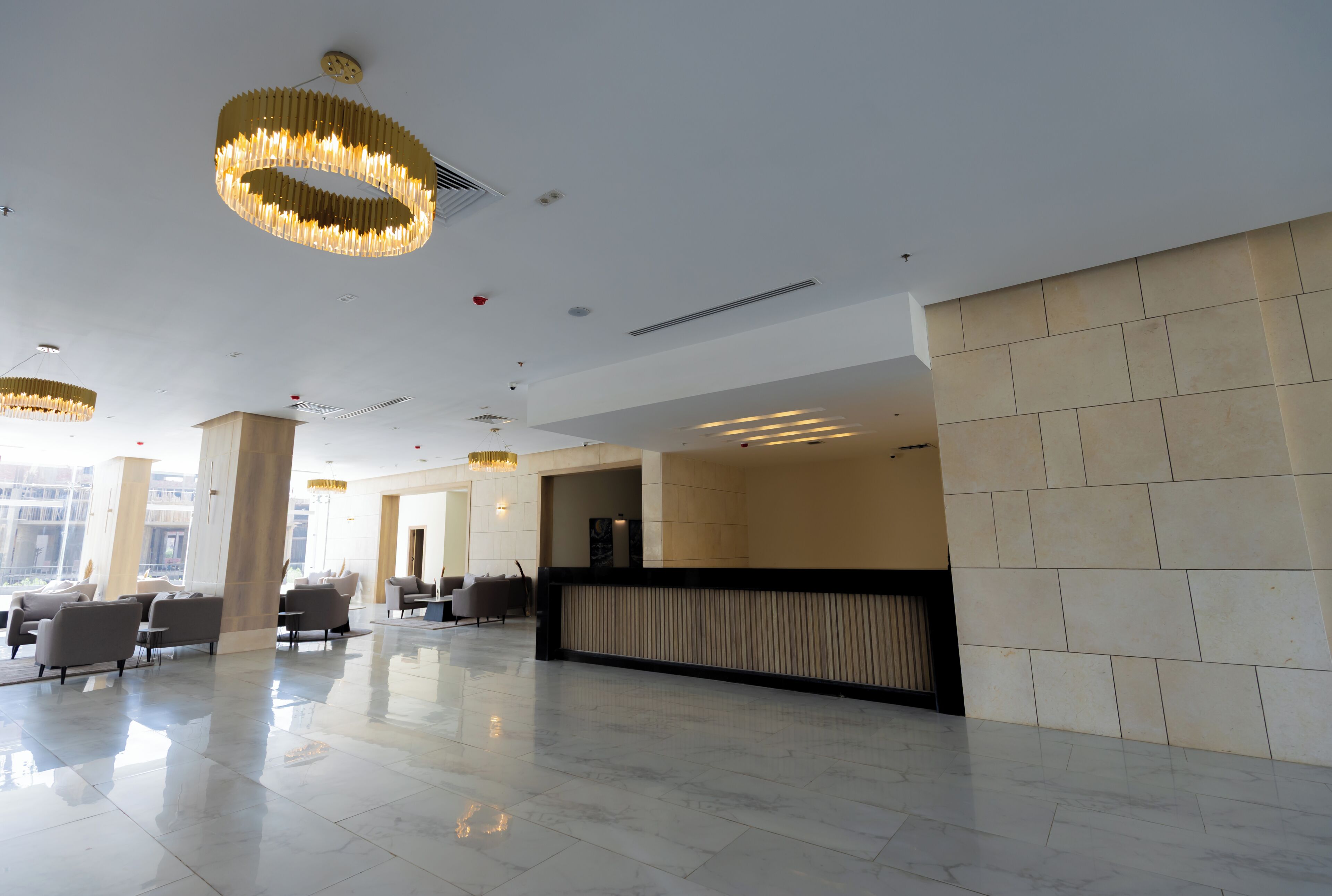 Um hall amplo com tetos altos, luminárias modernas e um balcão de recepção.