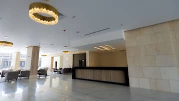 Um hall amplo com tetos altos, luminárias modernas e um balcão de recepção.
