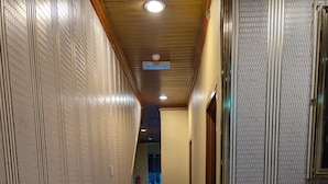 Um corredor com paredes estampadas, piso ladrilhado e teto com iluminação embutida.