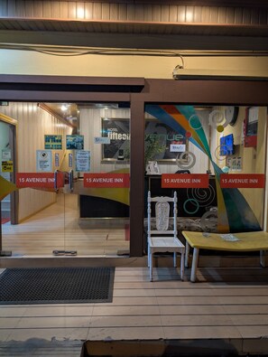 A entrada da 15 Avenue Inn, com uma mesa de recepção, uma cadeira e um banco do lado de fora.