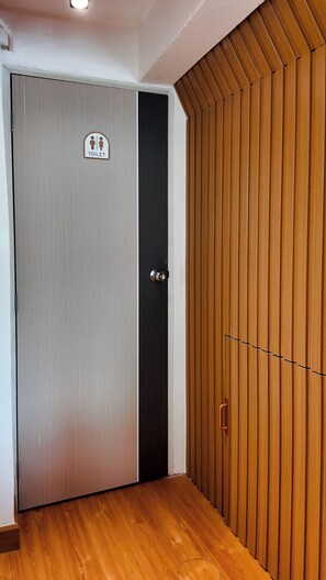 Um quarto com porta cinza, porta preta e parede com painel de madeira.