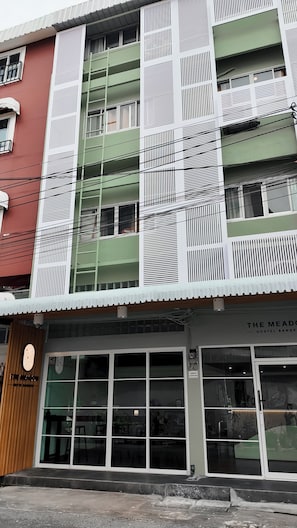 Um edifício de vários andares com fachada verde e molduras de janela brancas.