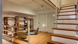 Um quarto com escada de madeira, estante e um banco acolchoado.