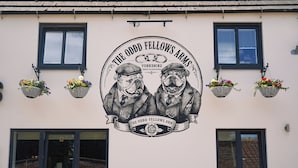 Um edifício com um emblema circular apresentando dois cães e o texto 'The Odd Fellows Arms Yorkshire Family & Friendship'.