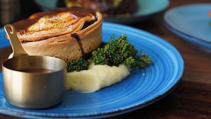 Um prato com purê de batata, brócolis e um pastel de carne.