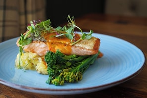 Um prato de comida com salmão, batatas e vegetais verdes.