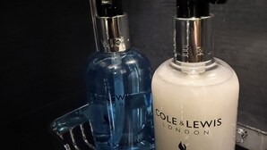 Dois frascos de produtos de higiene pessoal sobre uma prateleira de metal.