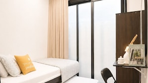 Quarto moderno com cama, escrivaninha e uma janela grande.