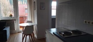 Uma cozinha compacta com uma mesa de jantar, uma cadeira e um fogão.